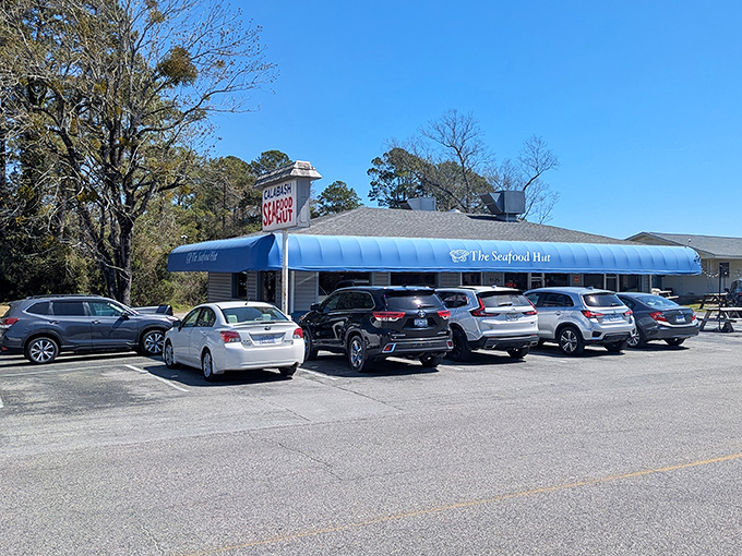 The blue awning beckons like a coastal lighthouse, promising seafood treasures within. License plates from across the Carolinas fill the parking lot daily.