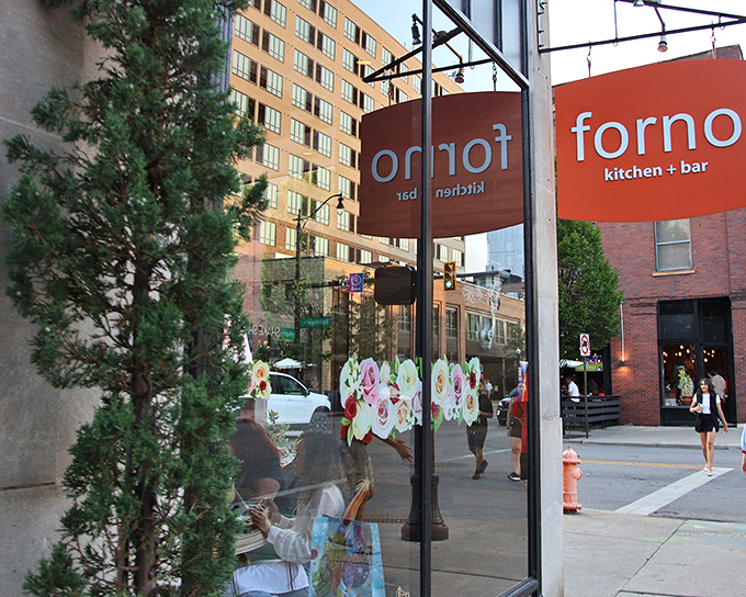 The bright orange patio barriers of Forno Kitchen + Bar stand out against downtown Columbus's urban landscape, beckoning hungry pedestrians like a culinary lighthouse.