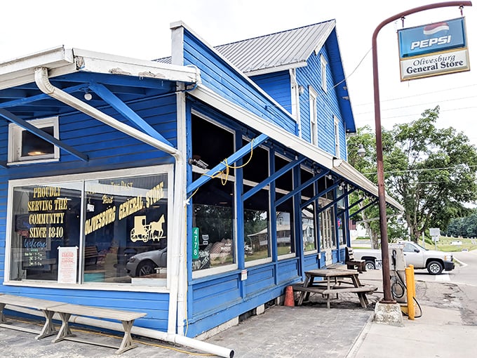 The blue clapboard exterior of Olivesburg General Store stands like a culinary lighthouse at a rural crossroads, beckoning hungry travelers with promises of sandwich perfection.