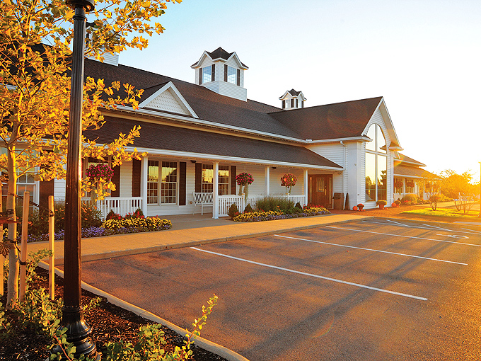 The classic white farmhouse exterior welcomes you like an old friend, promising comfort and satisfaction before you even step inside.