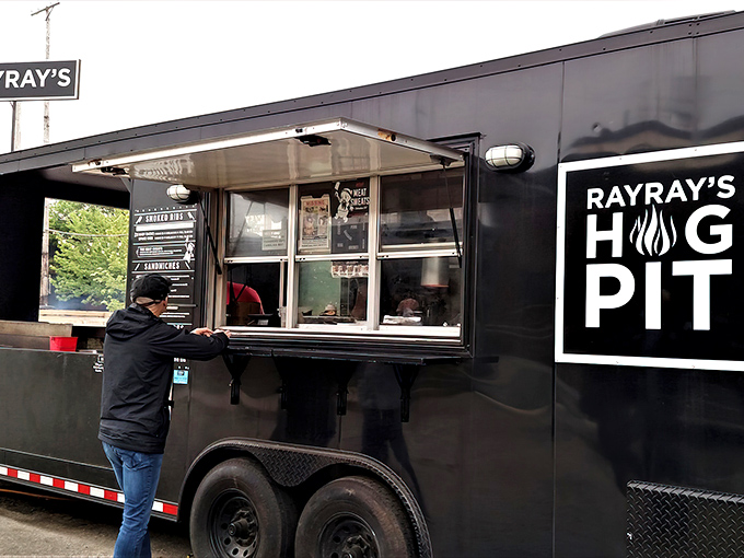 The black food truck of destiny awaits! Ray Ray's Hog Pit's sleek exterior promises smoky treasures within, drawing hungry pilgrims to its window like moths to a delicious flame.