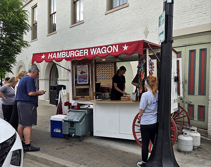 The iconic Hamburger Wagon stands proudly on Miamisburg's brick sidewalks, its red wheels and awning a beacon of burger hope for hungry passersby.