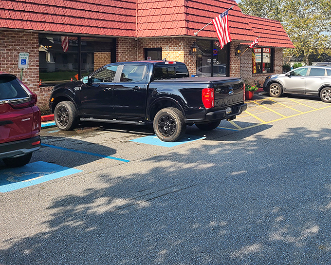 The American dream served daily: A charming brick exterior with patriotic flair, welcoming bench, and colorful flower pots that say "come on in, we've got something good cooking."