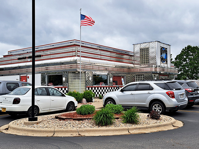 The gleaming stainless steel exterior of Gus's Diner stands like a time capsule from the 1950s, complete with checkered trim and an American flag proudly waving above.
