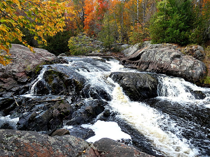 Nature's own watercolor masterpiece &ndash; autumn foliage frames the rushing copper-tinted waters as they tumble over ancient volcanic rock.