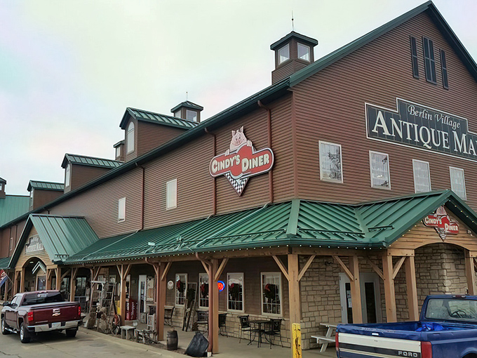 The grand barn-like exterior of Berlin Village Antique Mall stands as a beacon for treasure hunters, its distinctive green roof and cupolas promising adventures within.