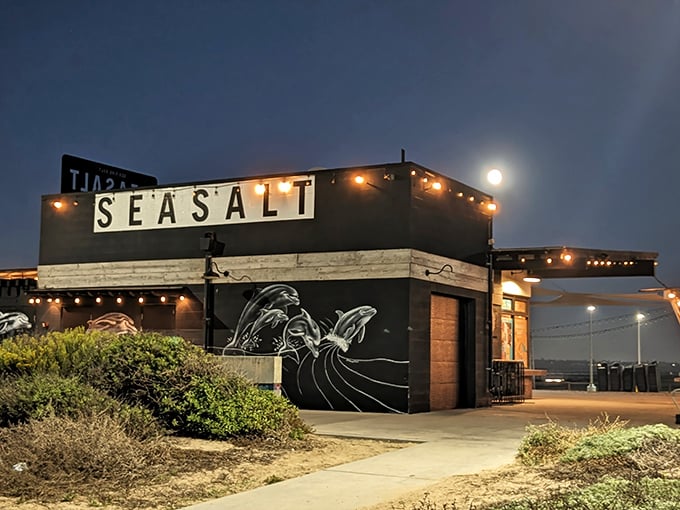 Sea Salt's moonlit exterior transforms into a coastal beacon for hungry beachgoers. String lights twinkle against the night sky, promising culinary delights inside.