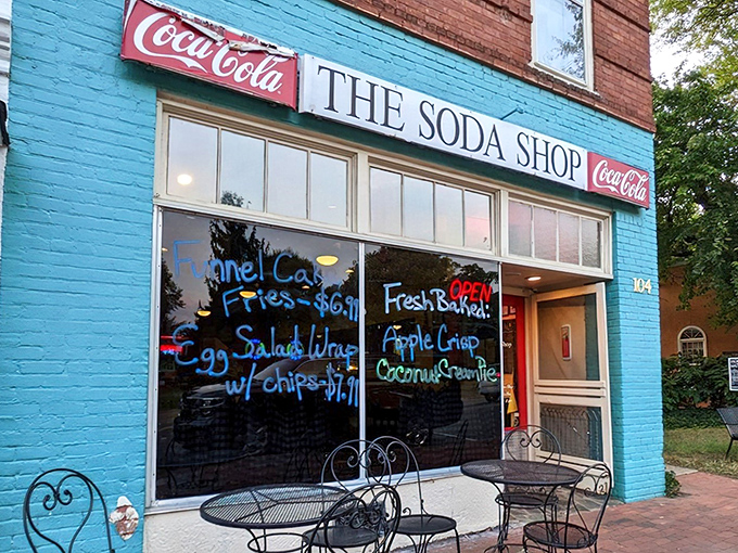 The turquoise facade of The Soda Shop stands like a portal to simpler times, complete with handwritten window promises of fish & chips and fresh-baked treats.