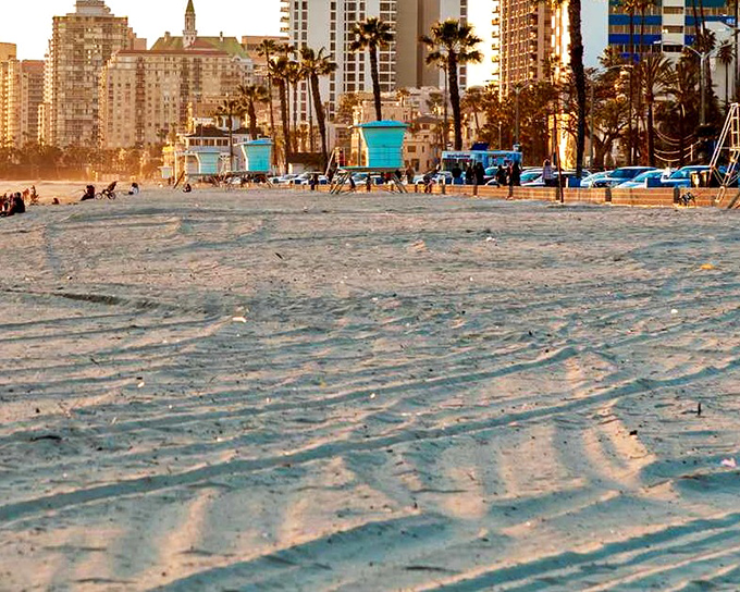 Golden hour transforms Long Beach's shoreline into a postcard-perfect scene, where turquoise lifeguard towers stand sentinel over rippling sands.
