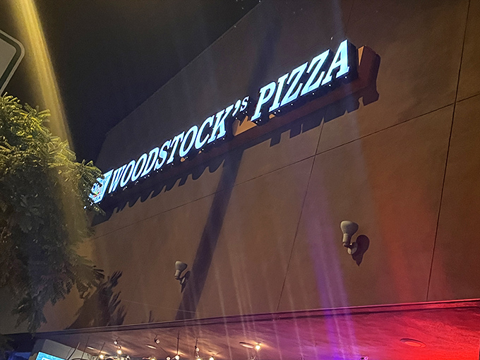 The neon glow of Woodstock's Pizza sign cuts through the night like a beacon for hungry travelers. Pizza paradise awaits.