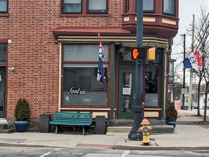 The charming exterior of Kitchen 101 beckons with its green door and vibrant flowers, like a culinary oasis on Chambersburg Street.