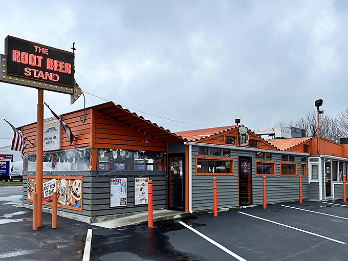 The iconic orange and gray exterior of The Root Beer Stand stands as a time capsule of Americana, beckoning hungry travelers with its vintage neon sign.