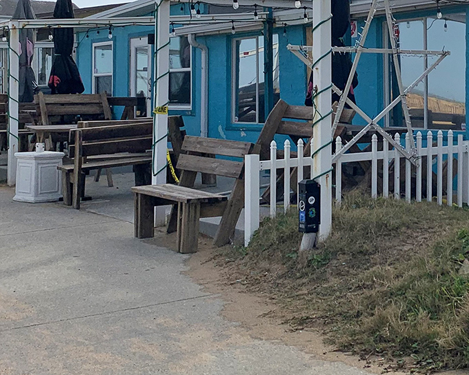 The little blue bungalow that could! Turtle Shack's charming exterior with rustic wooden benches invites you to slow down and savor coastal living at its finest.