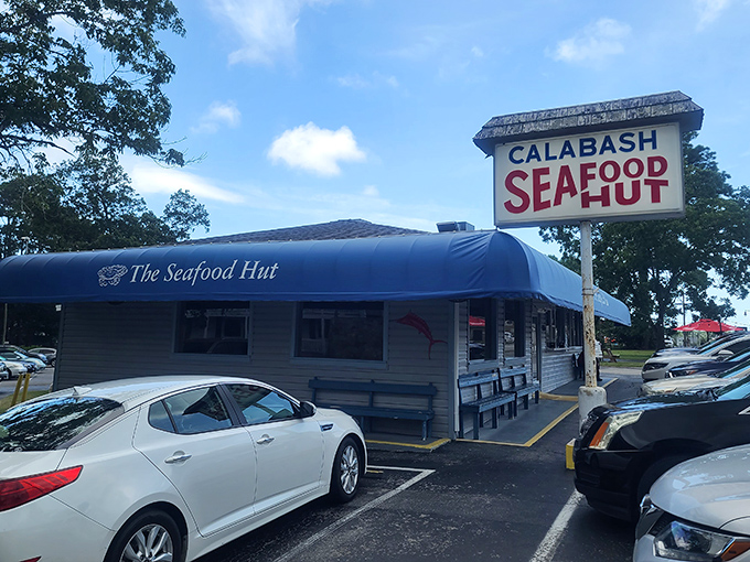 The blue awning beckons like a coastal lighthouse, promising seafood treasures within. License plates from across the Carolinas fill the parking lot daily.