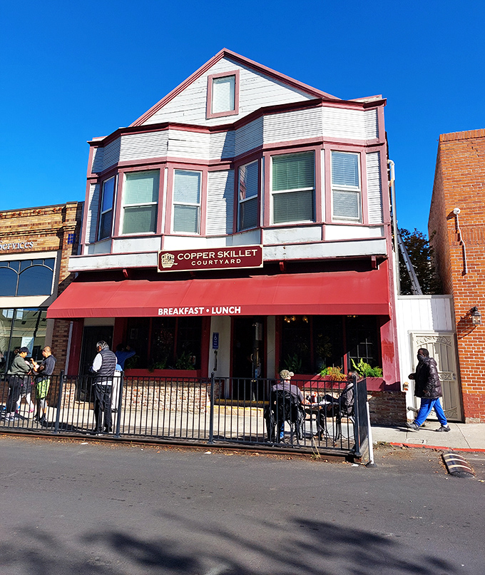 The charming facade of Copper Skillet Courtyard beckons with its distinctive red awning, promising comfort food treasures within this historic Martinez building.