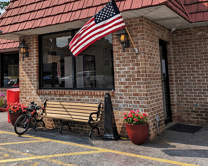 Classic Americana at its finest &ndash; a brick exterior with a welcoming bench, vibrant flower pots, and that iconic red roof that practically whispers "come hungry, leave happy."