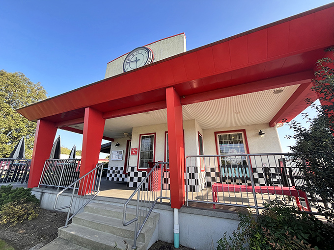 The classic red and white exterior of DJ's stands like a time portal to the 1950s, complete with vintage signage and stone landscaping.