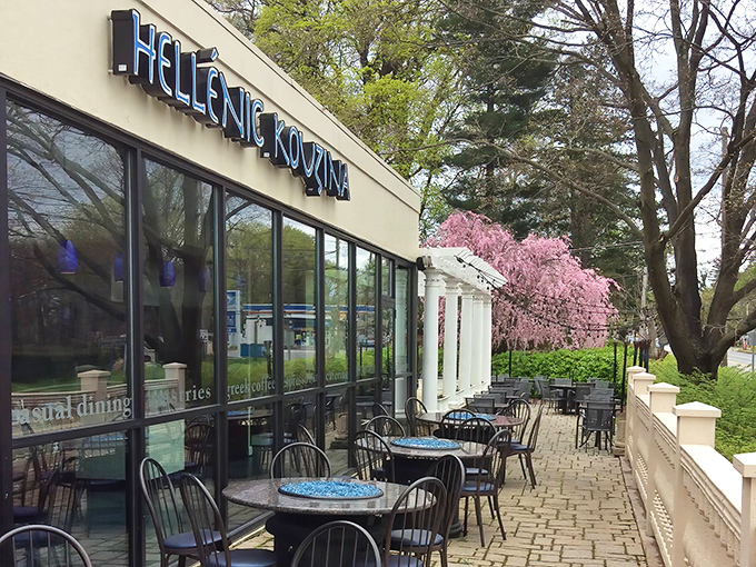 The blue sign beckons like a Mediterranean lighthouse against Pennsylvania greenery. Spring cherry blossoms add a touch of pink perfection to Hellenic Kouzina's inviting patio.