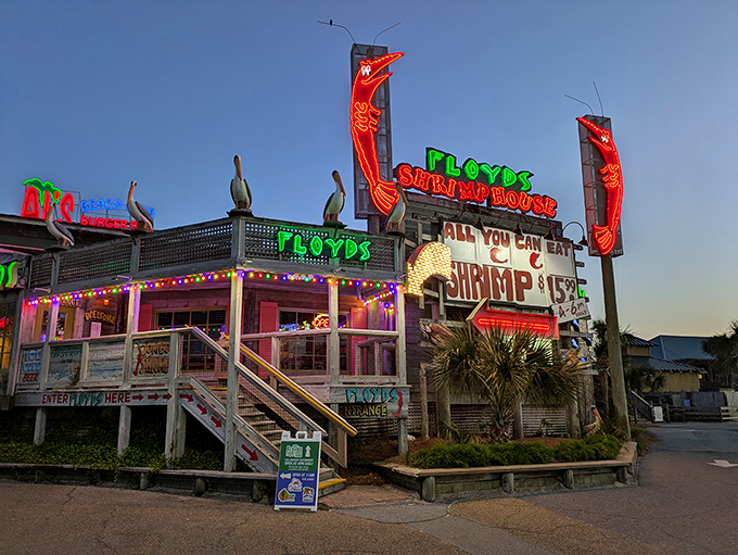 Neon dreams and pelican sentinels welcome you to Floyd's, where the weathered wood exterior promises authentic coastal delights inside.