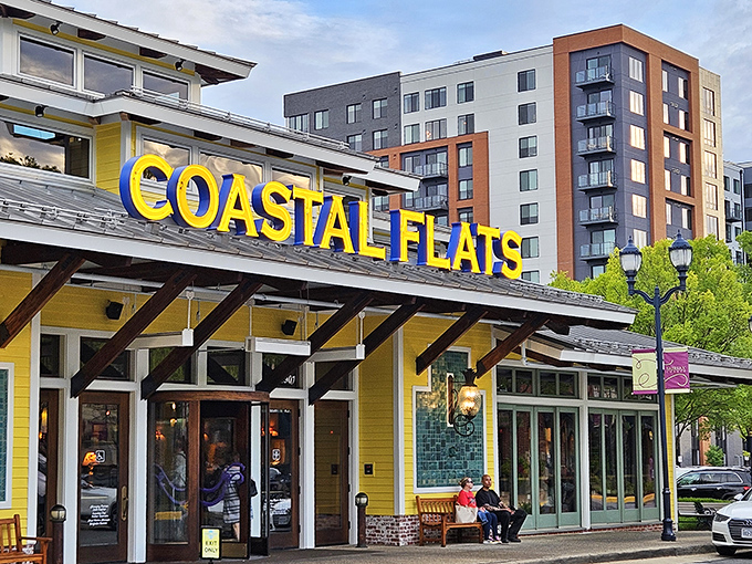 The sunshine-yellow exterior of Coastal Flats stands out like a cheerful beacon, promising seafood treasures within its nautical embrace.