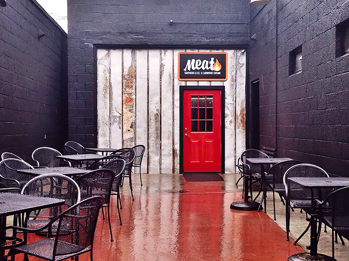 That bright red door between black walls isn't just an entrance&mdash;it's a portal to barbecue nirvana. The outdoor seating area beckons with the promise of smoky delights.