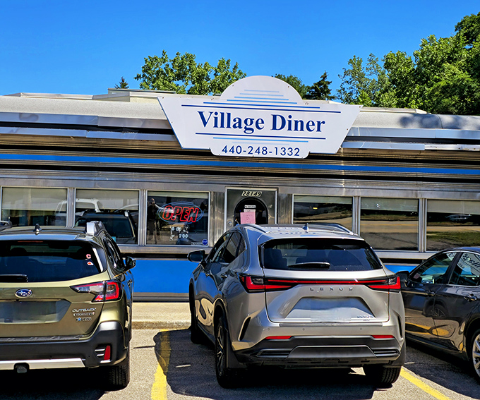 The classic blue and white exterior of Village Diner stands like a time capsule of Americana, beckoning hungry travelers with promises of comfort food perfection.