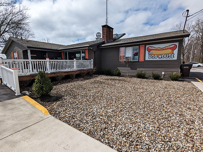 A ranch-style building with a white porch railing and colorful sign beckons like an old friend. This unassuming hot dog haven proves that culinary treasures often hide in plain sight.