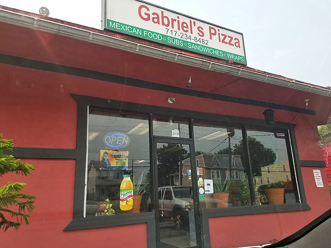 The bright red exterior of Gabriel's Pizza stands out like a beacon of hope for the hungry traveler. Simple signage promises multiple culinary adventures under one roof.