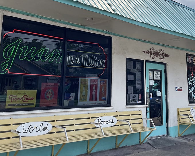 The neon sign beckons like an old friend – "Juan in a Million" glows against the simple white exterior, while the "World Famous" bench outside tells you everything you need to know.