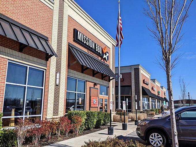 The American flag stands tall outside Mission BBQ, a patriotic beacon for hungry Tennesseans seeking smoky salvation in Murfreesboro's retail landscape.