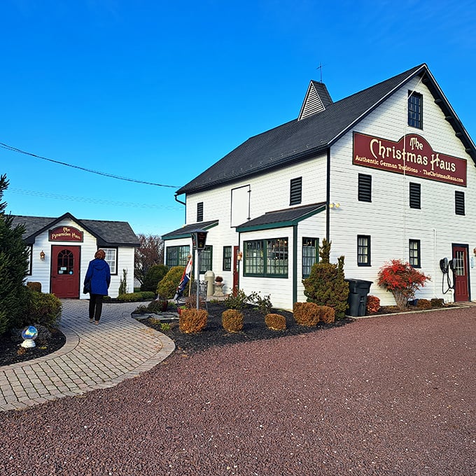 The white barn-like exterior of The Christmas Haus stands proudly against a blue Pennsylvania sky, its red sign promising year-round holiday magic.