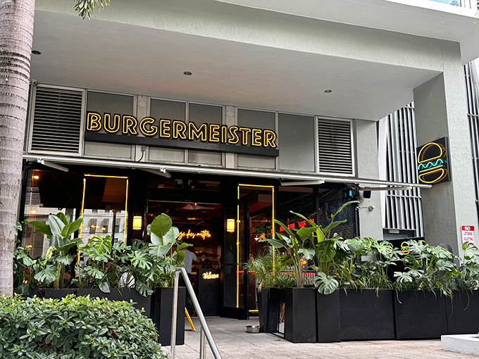 Burgermeister's glowing yellow sign beckons like a burger lighthouse amid the urban jungle of Brickell. Lush greenery frames the entrance, promising a tropical twist on comfort food.