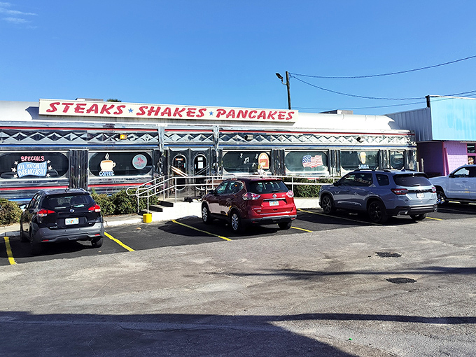 The gleaming silver exterior of All American Diner shines like a beacon of breakfast hope on Panama City Beach, promising "STEAKS * SHAKES * PANCAKES" in bold red letters.
