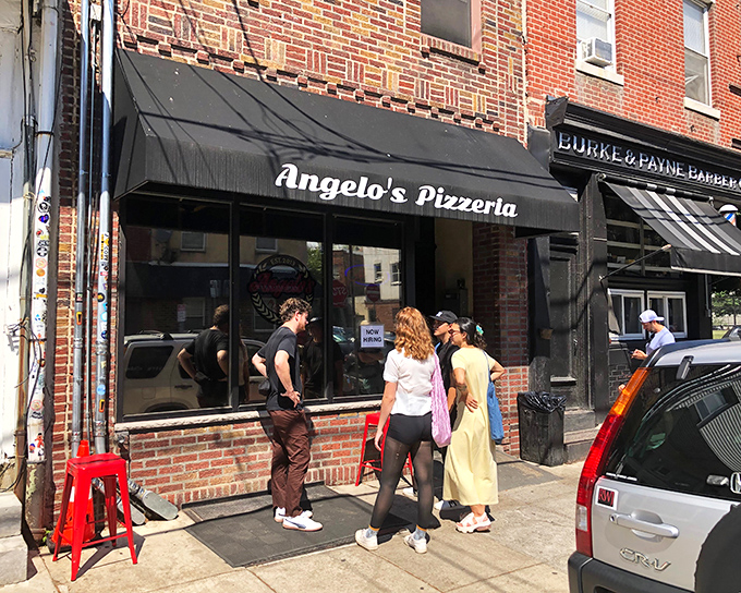 The unassuming storefront of Angelo's Pizzeria in South Philly, where culinary dreams come true behind that modest black awning.