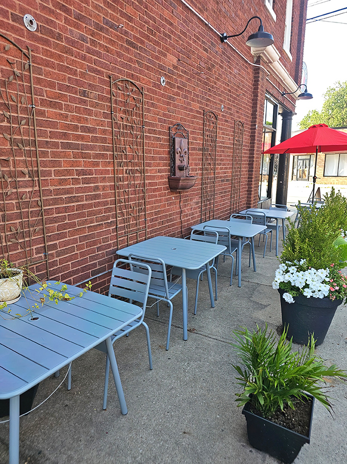 The exposed brick exterior of Peppers Italian Restaurant sets the stage for a cozy outdoor dining area, featuring light blue tables, lush greenery, and a bold red umbrella&mdash;all perfect for enjoying fantastic food without the fuss.