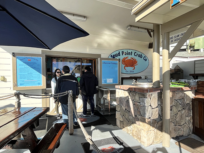 The unassuming exterior of Spud Point Crab Company, where blue umbrellas and wooden picnic tables promise seafood paradise. That vintage truck knows what's up.