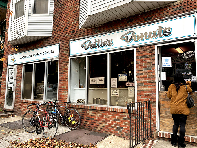 The unassuming brick storefront of Dottie's Donuts in West Philly, where vegan pastry magic happens daily behind that retro blue sign.
