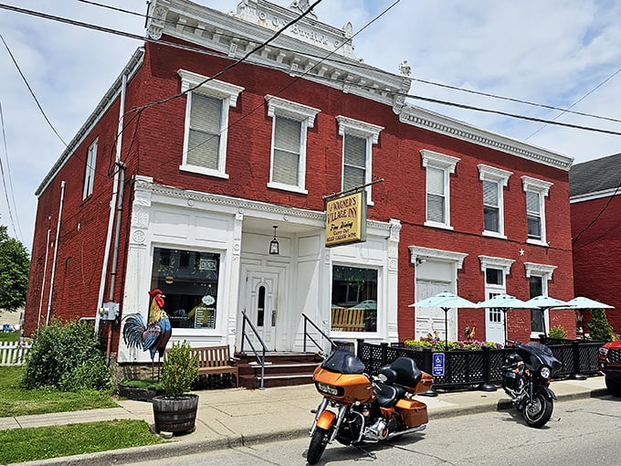 The red brick exterior of Wagner's Village Inn stands proudly in Oldenburg, complete with a colorful rooster guardian and motorcycles that signal good taste is parked here.