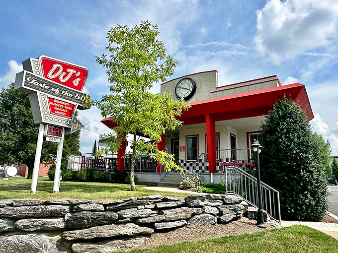 The classic red and white exterior of DJ's stands like a time portal to the 1950s, complete with vintage signage and stone landscaping.