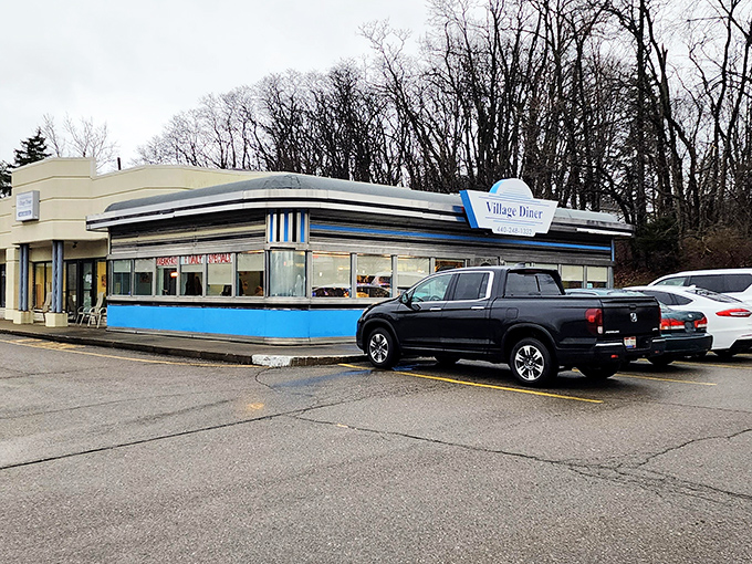 The classic blue and white exterior of Village Diner stands like a time capsule of Americana, beckoning hungry travelers with promises of comfort food perfection.