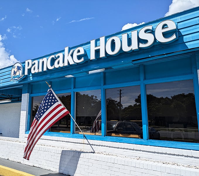 The cheerful blue facade of My Island Pancake House stands proudly against Florida's sky, American flag waving a warm welcome to hungry visitors.