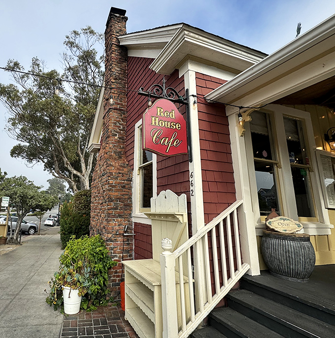The crimson cottage beckons like a storybook invitation, its white trim and welcoming porch promising comfort before you've even stepped inside.