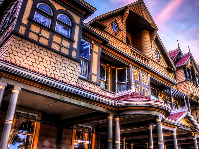 The Winchester Mystery House glows with eerie elegance at night, its Victorian fa&ccedil;ade hiding architectural oddities that would make M.C. Escher scratch his head in confusion.