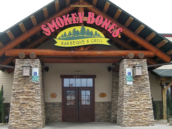 The rustic lodge-style exterior of Smokey Bones beckons meat lovers with its stone facade and distinctive peaked roof.