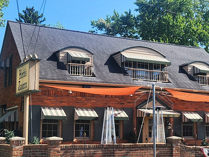 The charming brick exterior of Herb's Tavern, with its distinctive dormered windows, looks like a storybook cottage that happens to serve legendary burgers.