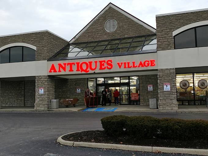 The stone facade of Antiques Village stands like a temple to nostalgia, its bold red sign a beacon to treasure hunters across Ohio.