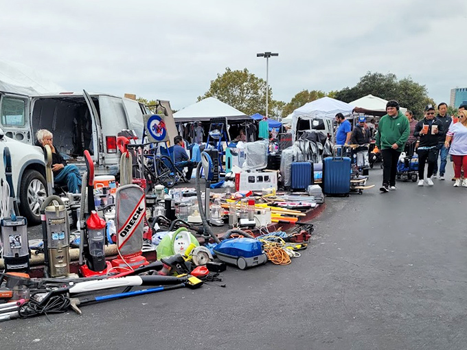Treasure hunting begins under blue canopies where sports jerseys hang like championship banners above tables of potential finds.