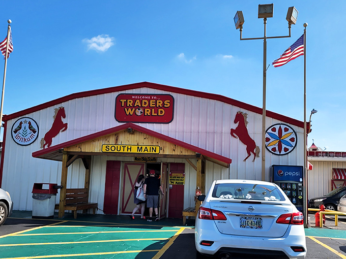 The iconic red and white barn facade of Traders World welcomes treasure hunters with its distinctive horse silhouettes and promise of wonders within.