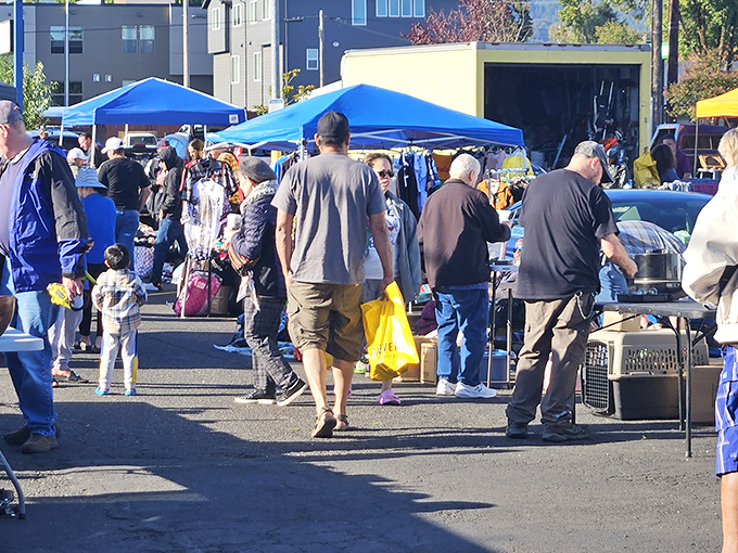 Treasure hunters navigate a sea of blue canopies, where one person's castoffs become another's prized possessions. Portland's weekend ritual of discovery unfolds.