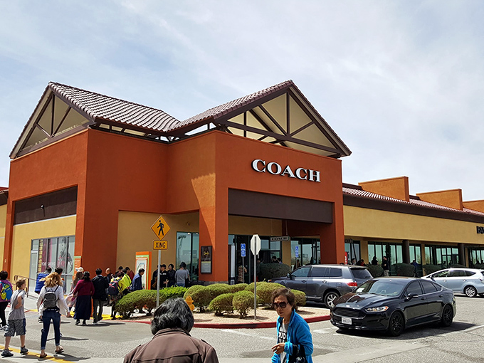 The Coach store at Barstow Outlets stands like a retail oasis in the desert, complete with a line of eager bargain hunters ready for their designer fix.